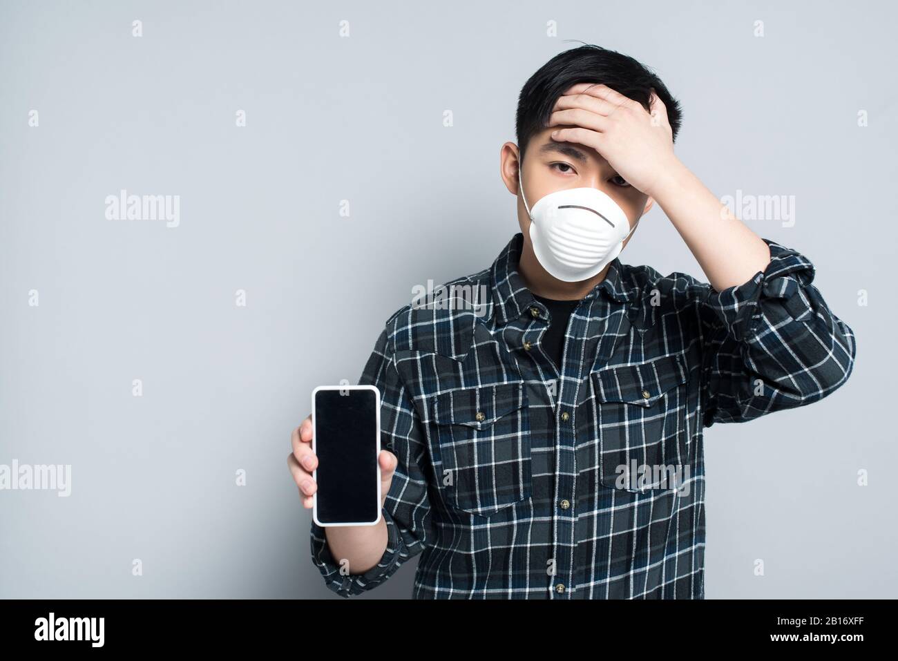 young asian man in respirator mask touching forehead while showing ...