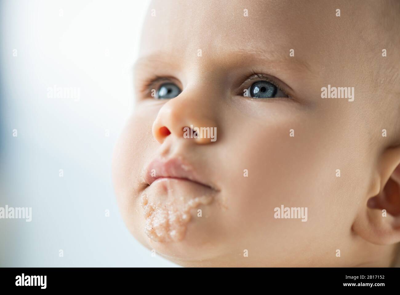 Portrait of cute infant with soiled mouth with baby food isolated on ...