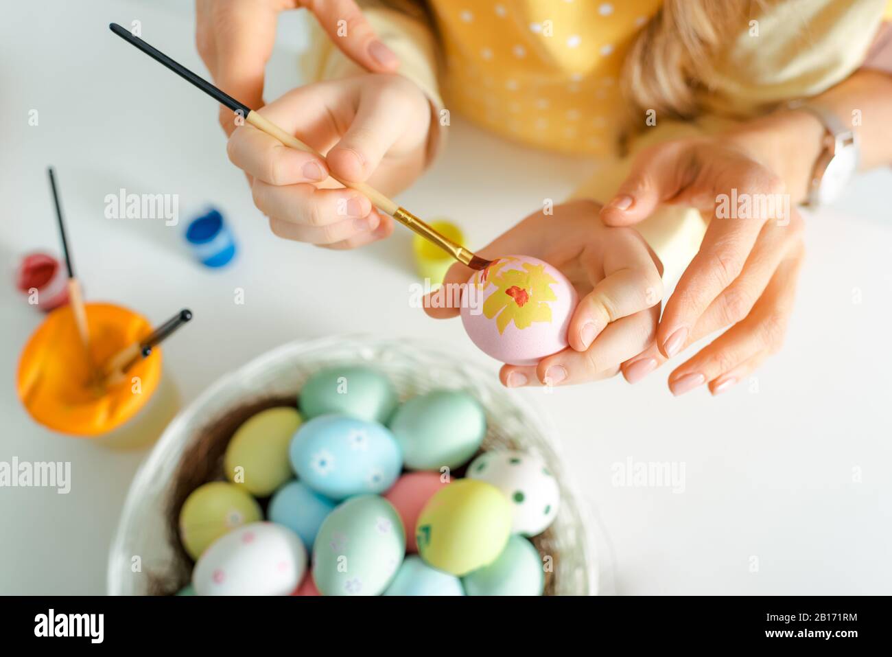 top view of kid painting easter egg near mother on white Stock Photo - Alamy