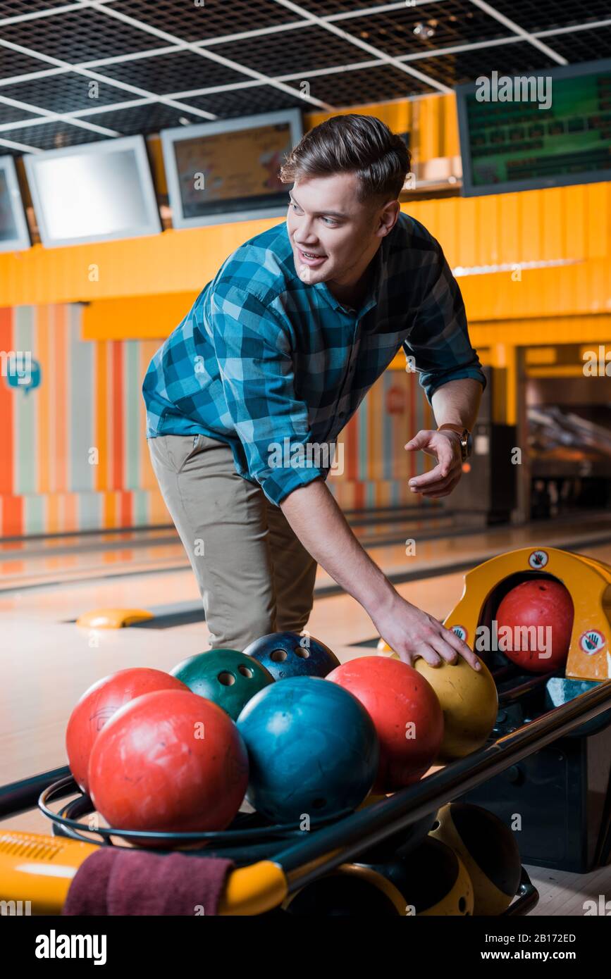 handsome smiling man taking bowling ball in bowling club Stock Photo ...