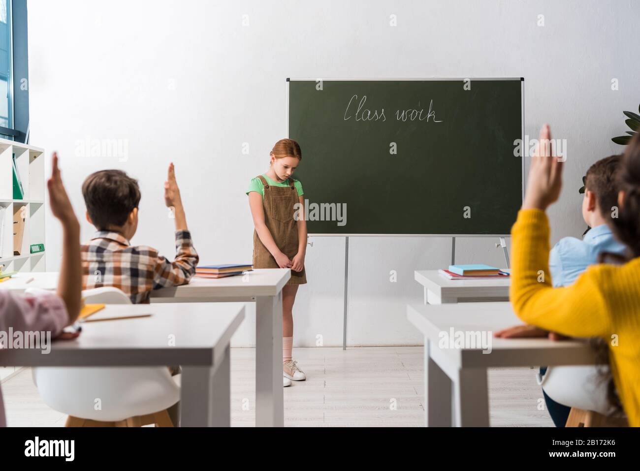 selective focus of schoolkid standing near chalkboard with class work ...