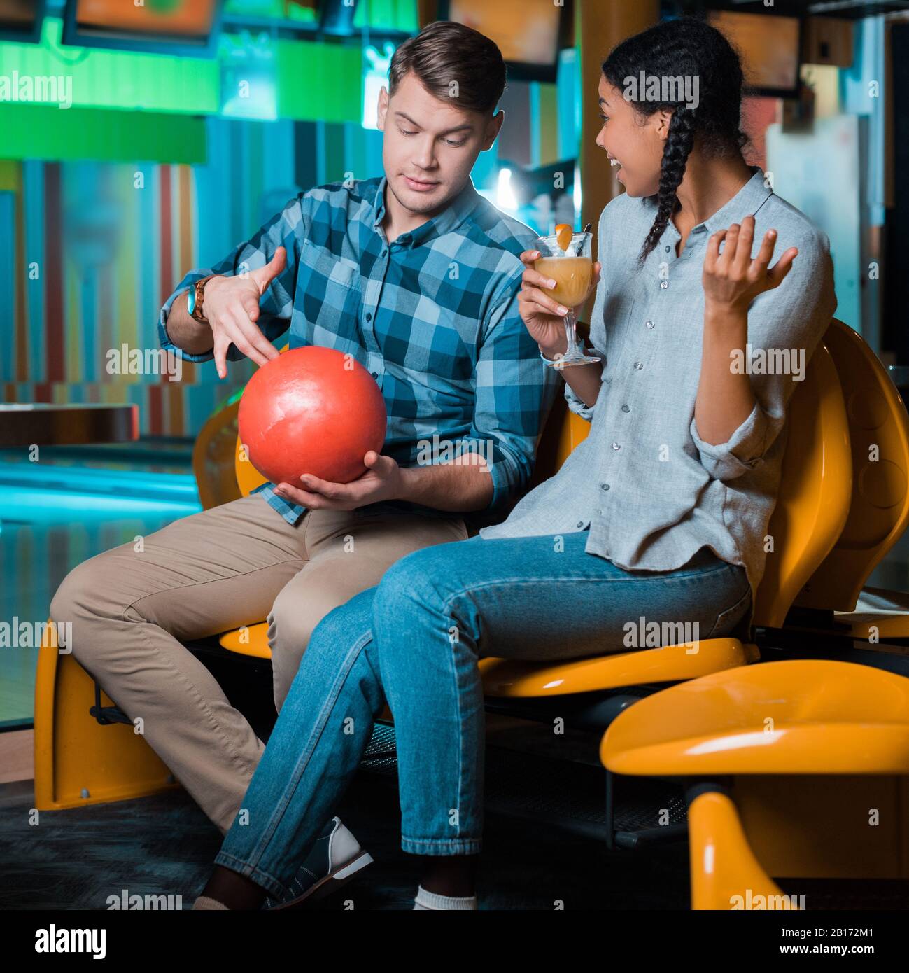 smiling african american girl holding glass of cocktail while boyfriend ...