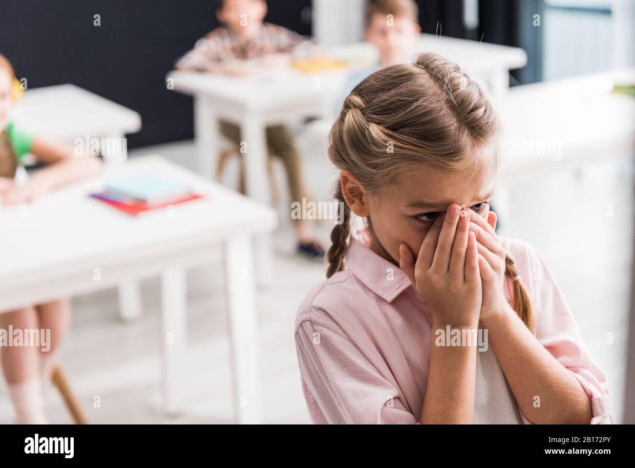 selective focus of upset schoolkid crying near classmates, bullying ...