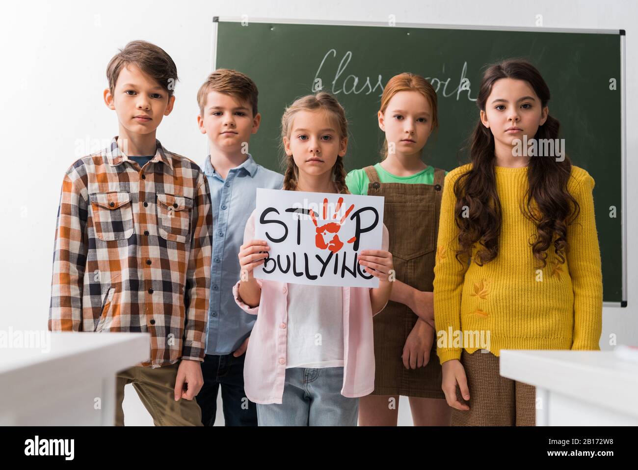 selective focus of schoolkids holding placard with stop bullying ...