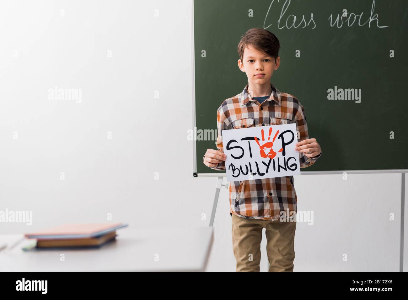 selective focus of schoolboy holding placard with stop bullying ...