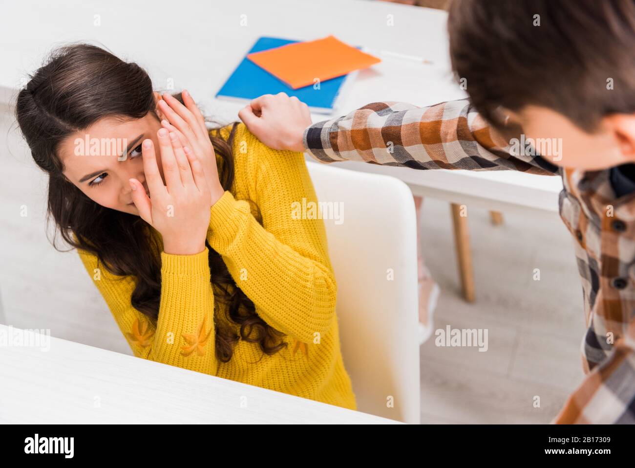 selective focus of cruel schoolboy bullying scared schoolgirl in ...
