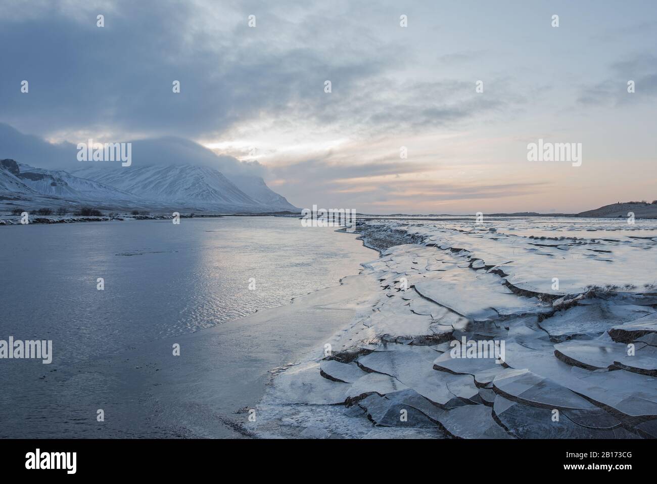 Icy river bank and snow covered mountains in Iceland Stock Photo - Alamy