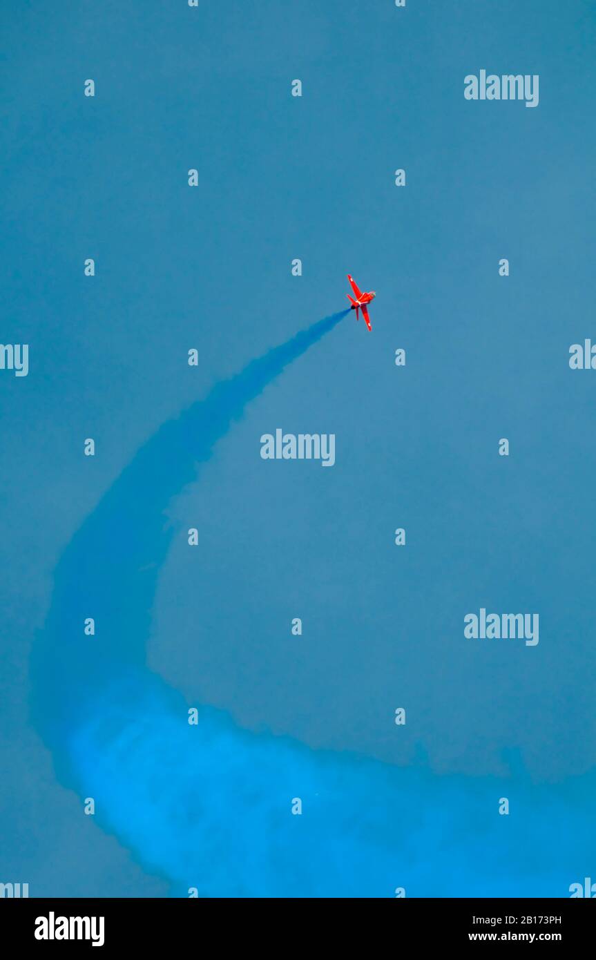 Red Arrow Jet Display With A Blue Smoke Vapour Trail Stock Photo - Alamy