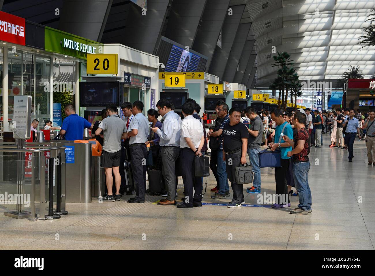 Passengers queue at the ticket gates in the waiting hall to board a ...