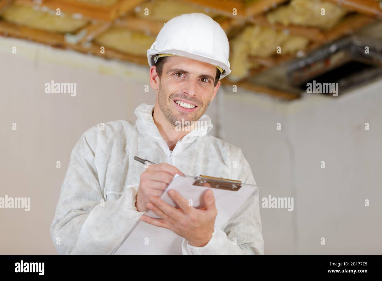 construction worker in overalls writing on a clipboard Stock Photo - Alamy
