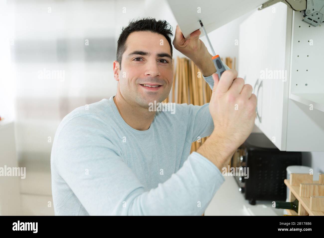 man posing while fixing cupboard hinges Stock Photo - Alamy