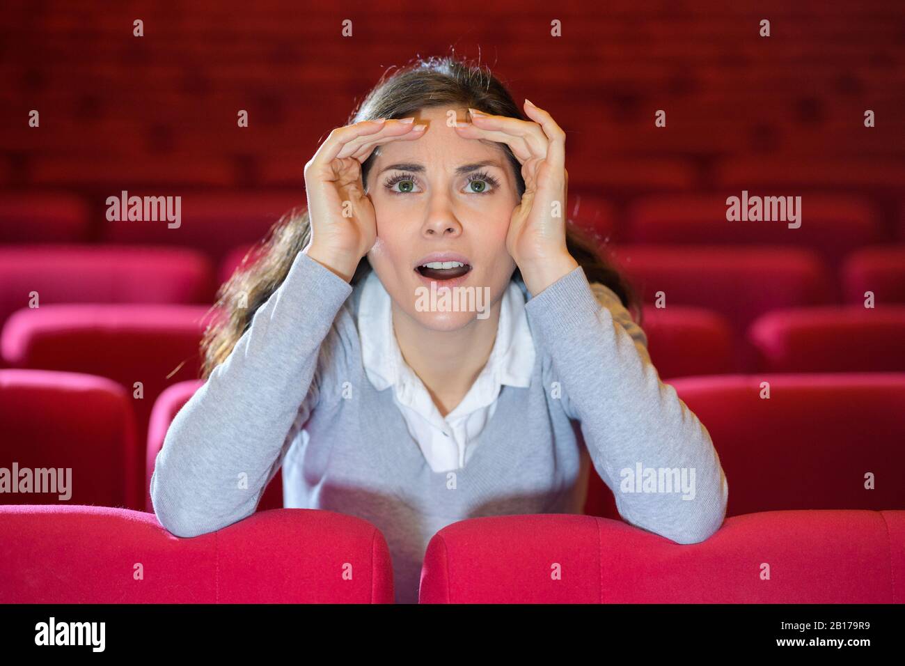 woman with shocking facial expression sitting at theater Stock Photo ...