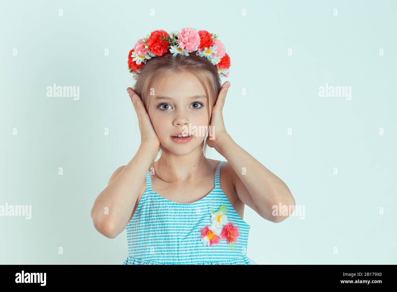 Portrait of smiling cute girl covering ears with her hands. Happy child ...