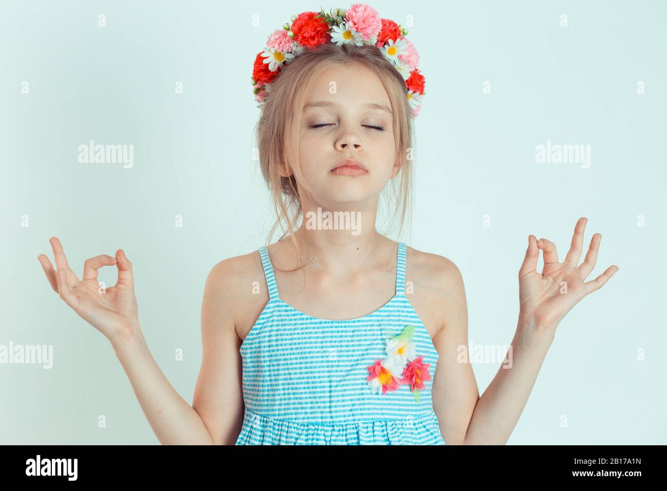 Cute kid girl with eyes closed holding hands up in meditation pose ...