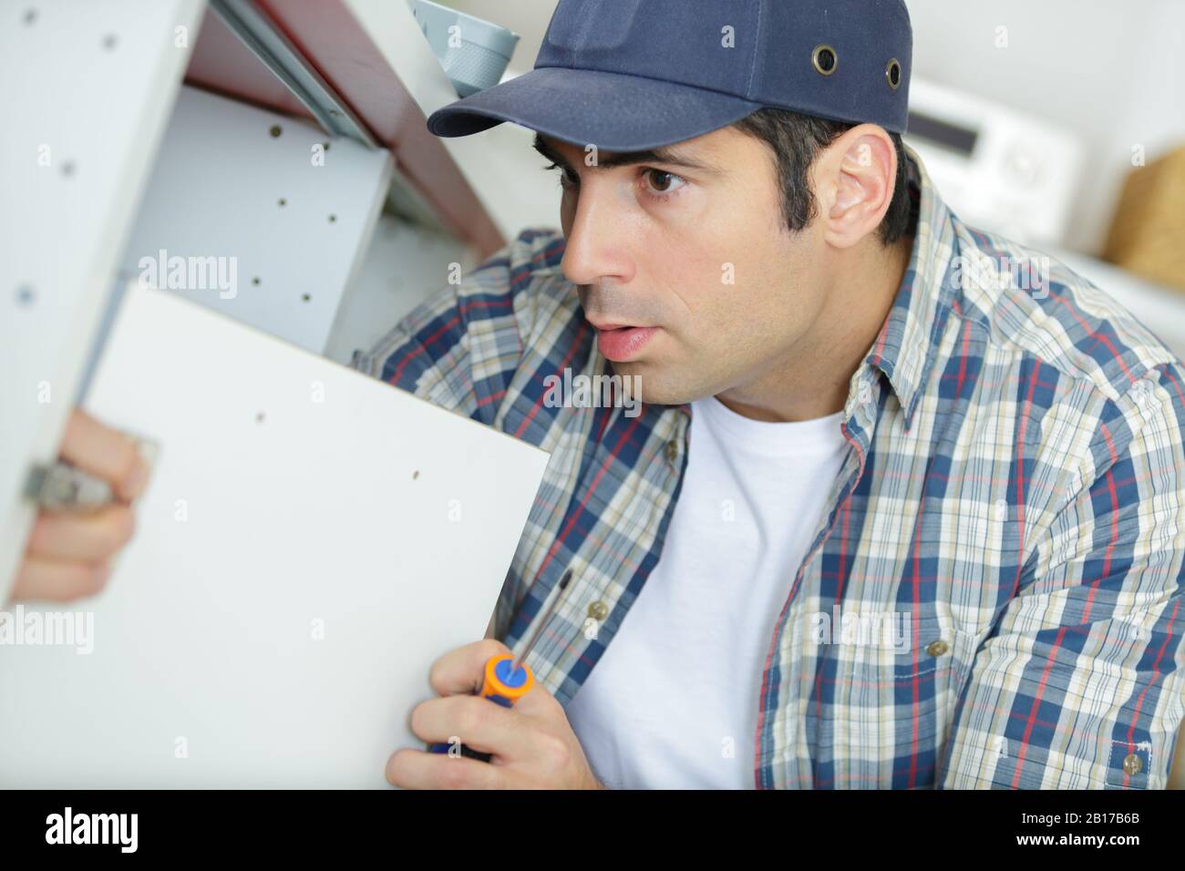 man fixing a wood door cupboard Stock Photo - Alamy