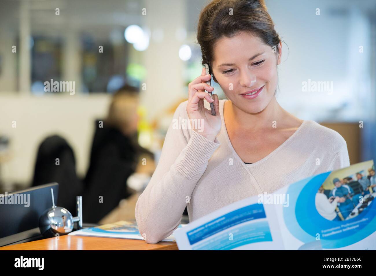 woman reading brochure and making telephone enquiry Stock Photo - Alamy