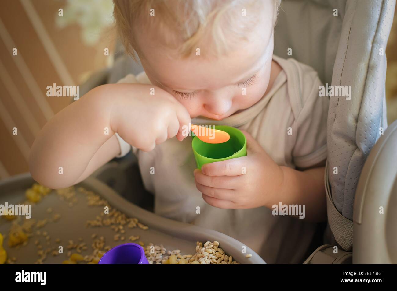small kid pours toy yellow spoon ful in cup. Games with products ...