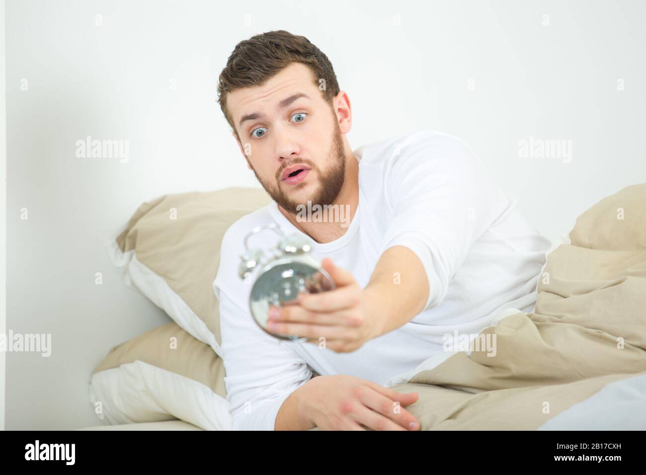 man with shocking facial expression holding an alarm clock Stock Photo ...