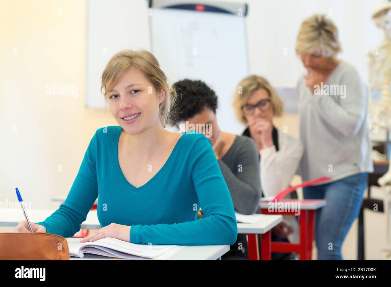 portrait of young adult sat at desk in classroom Stock Photo - Alamy