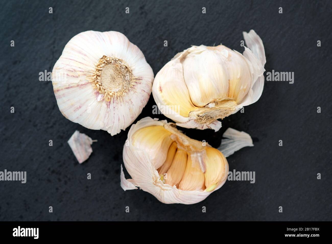 Garlic on a black background top view. Two heads of garlic, one whole ...