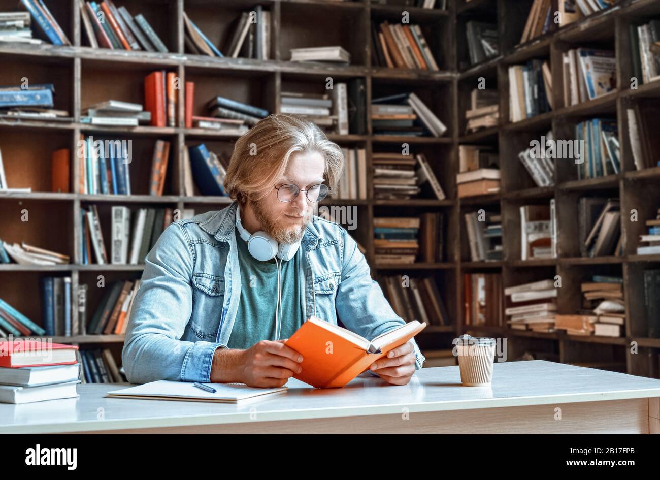 Serious bearded young man glasses sit library read book hobby education ...