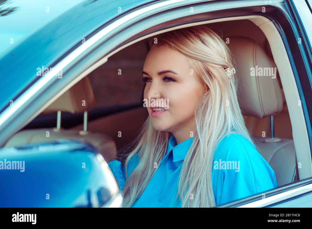 Driving around city. Young attractive woman smiling and looking ...