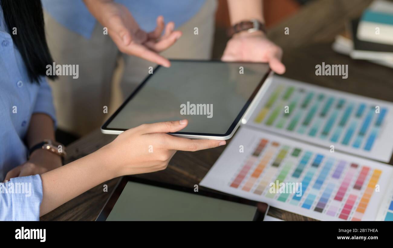 Close up view of young designer team consulting on their project with mock up tablet and colour ...