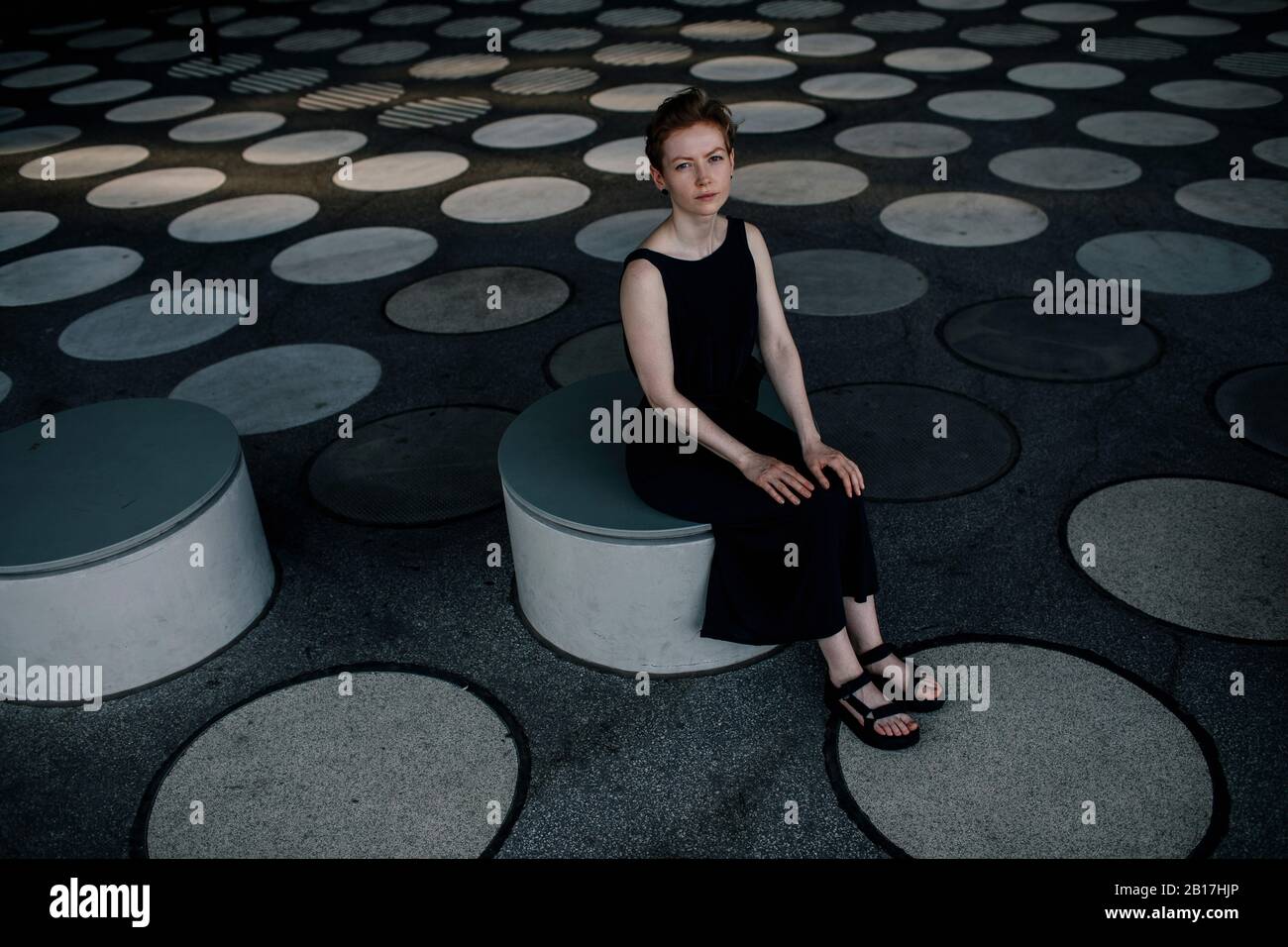 Elegant woman sitting on round bench in futuristic architecture Stock ...