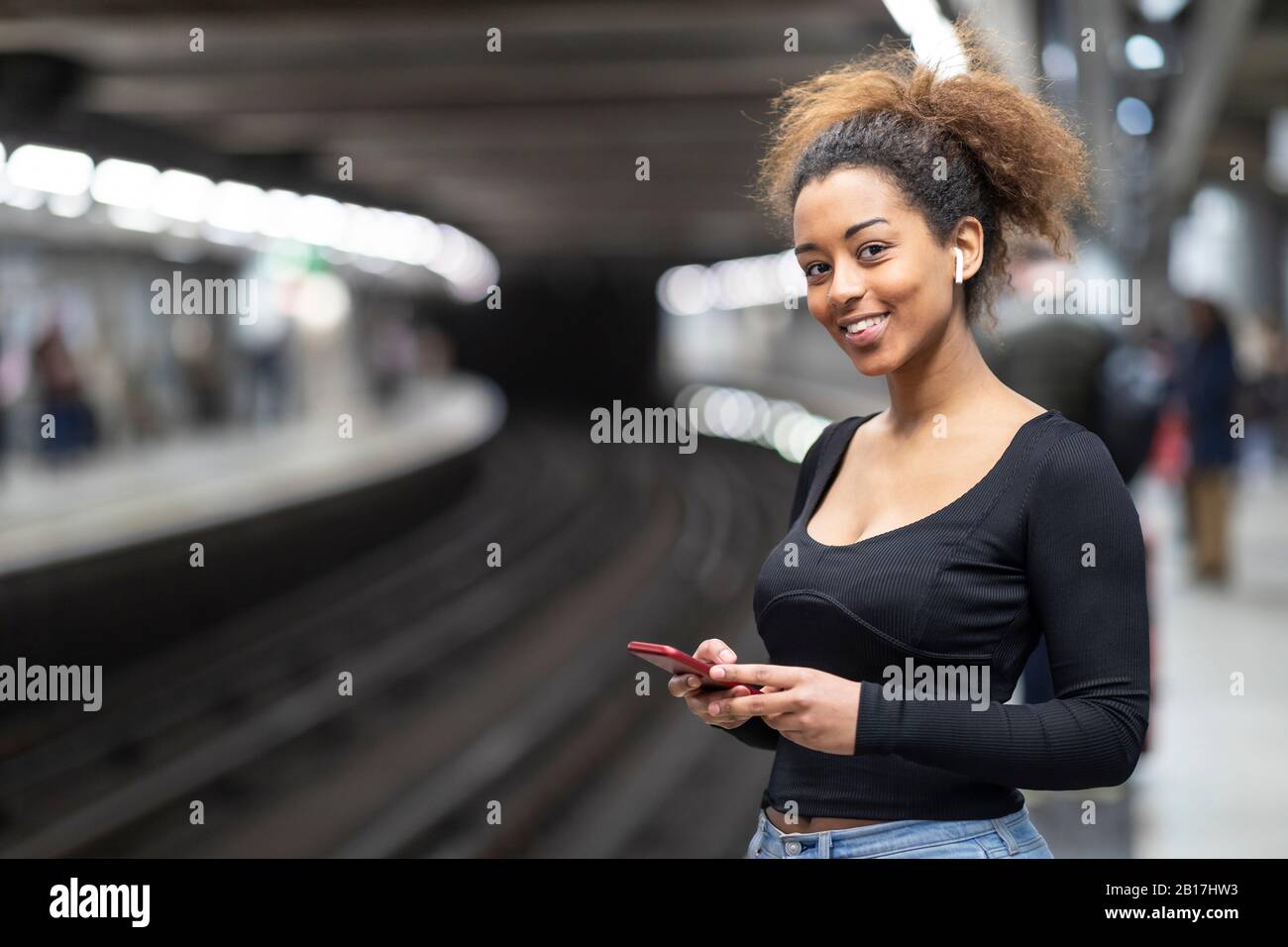 Portrait happy woman earphones subway station platform hi-res stock ...