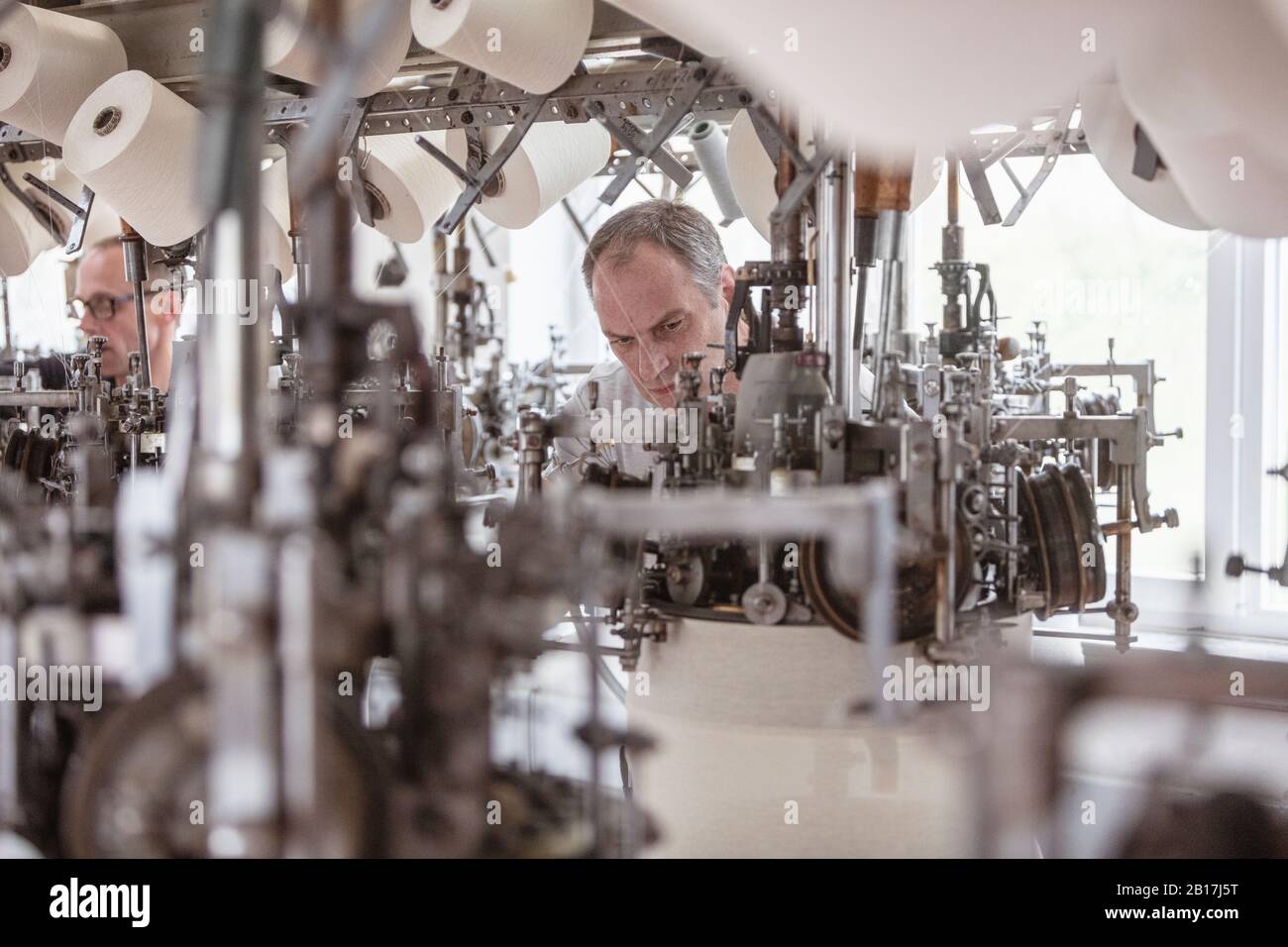 Two men at a machine in a textile factory Stock Photo - Alamy