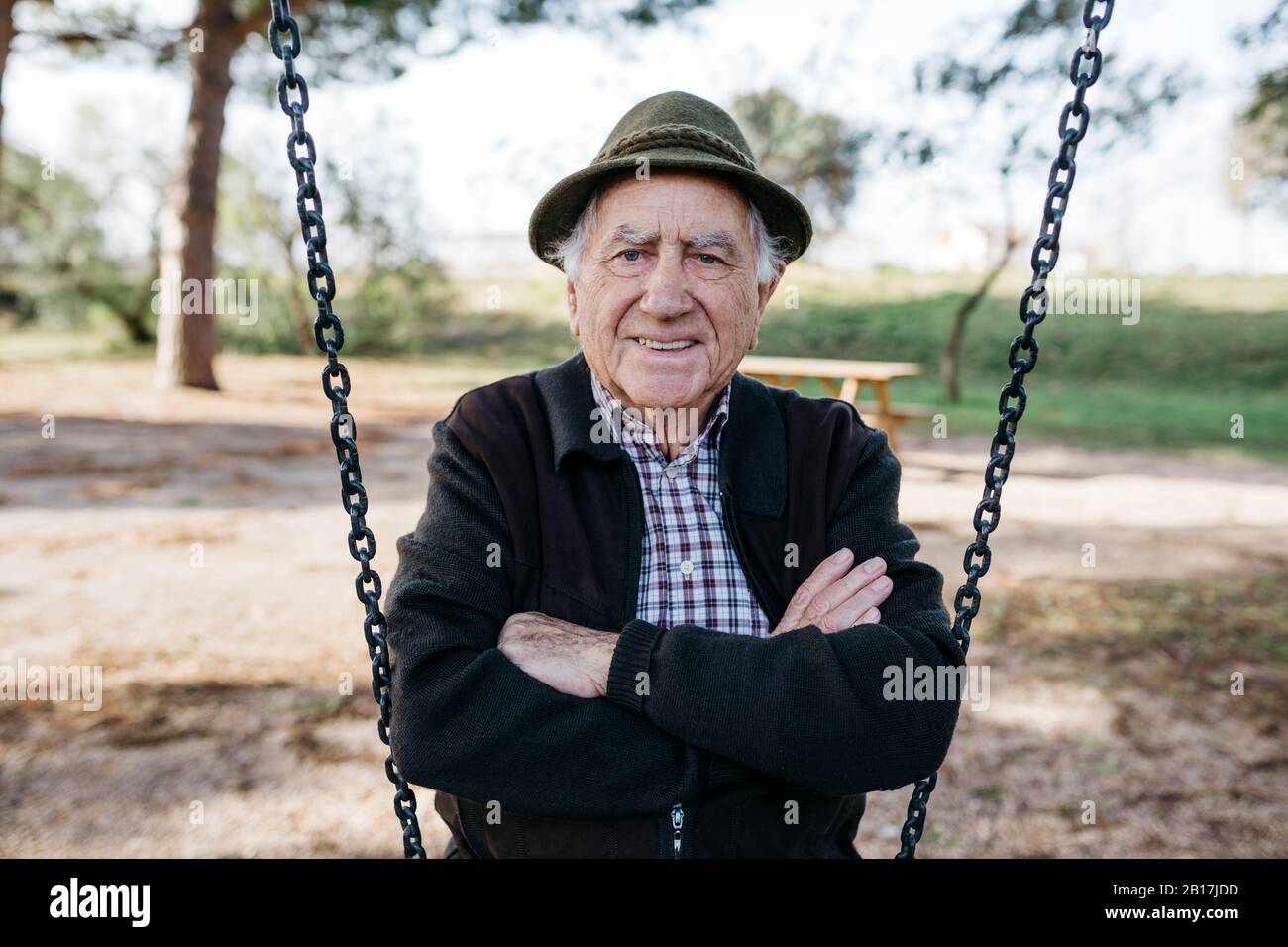 Old man sitting on swing in park, with arms crossed Stock Photo - Alamy