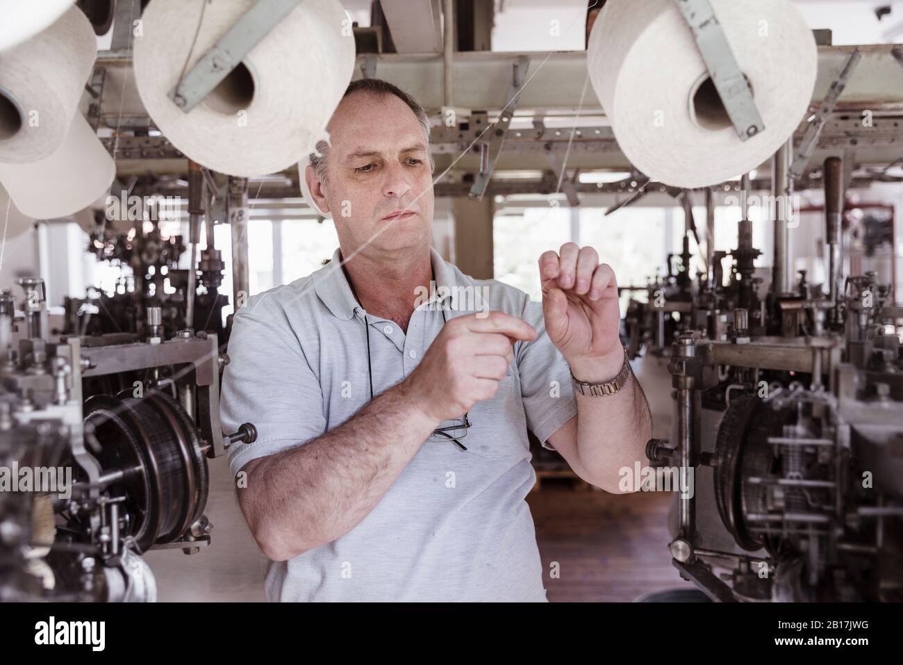 Man working with cotton reel in a textile factory Stock Photo - Alamy
