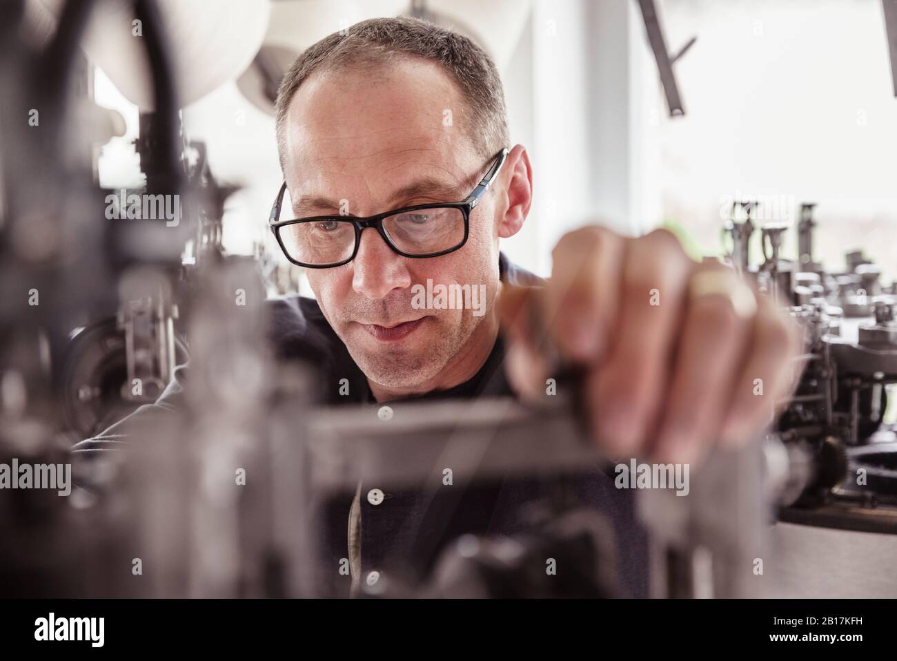 Portrait of focused man working at a machine in a textile factory Stock ...