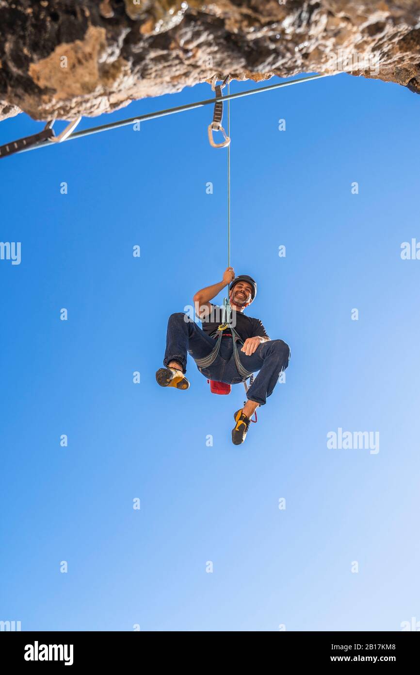 Portrait of smiling climber abseiling from rock face Stock Photo - Alamy