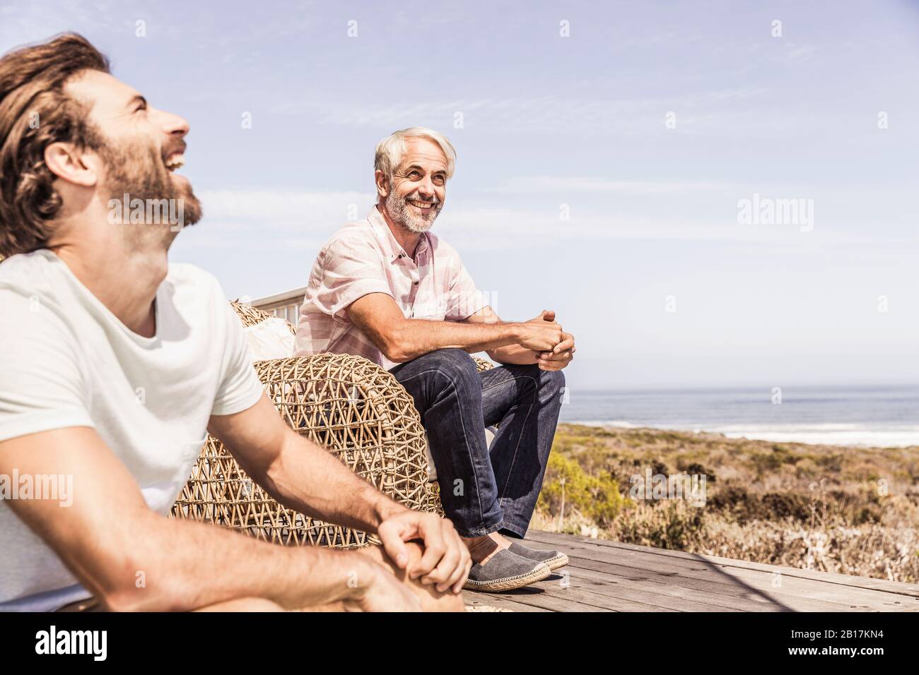 Father and adult son hanging out and having fun together on a terrace ...