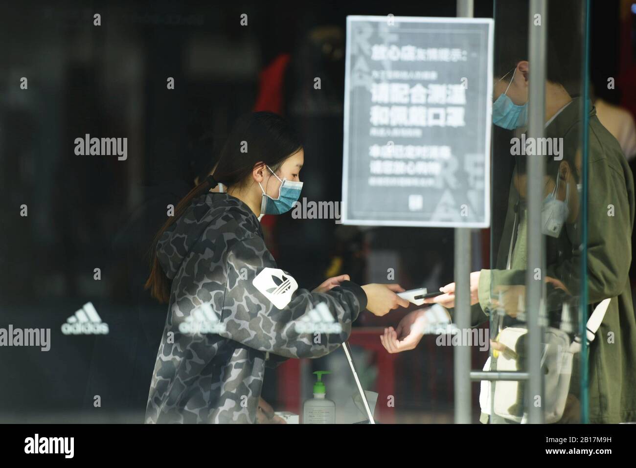 A Chinese clerk checks the body temperature of a customer for ...