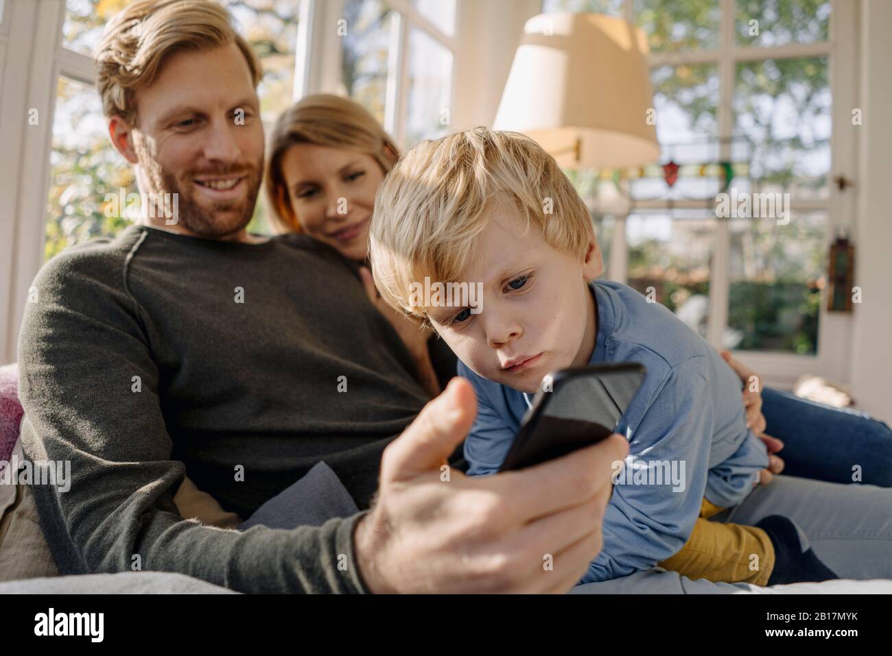 Happy family using cell phone in sunroom at home Stock Photo - Alamy