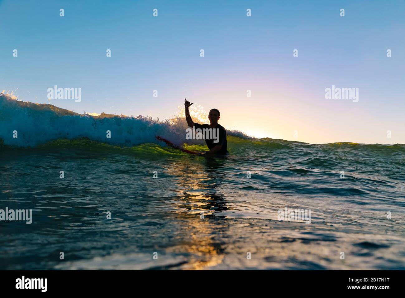 Surfer making surfer sign sitting on surfboard, Bali, Indonesia Stock ...