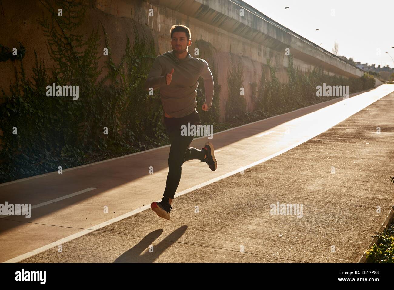 Man running on a road in sunlight Stock Photo - Alamy