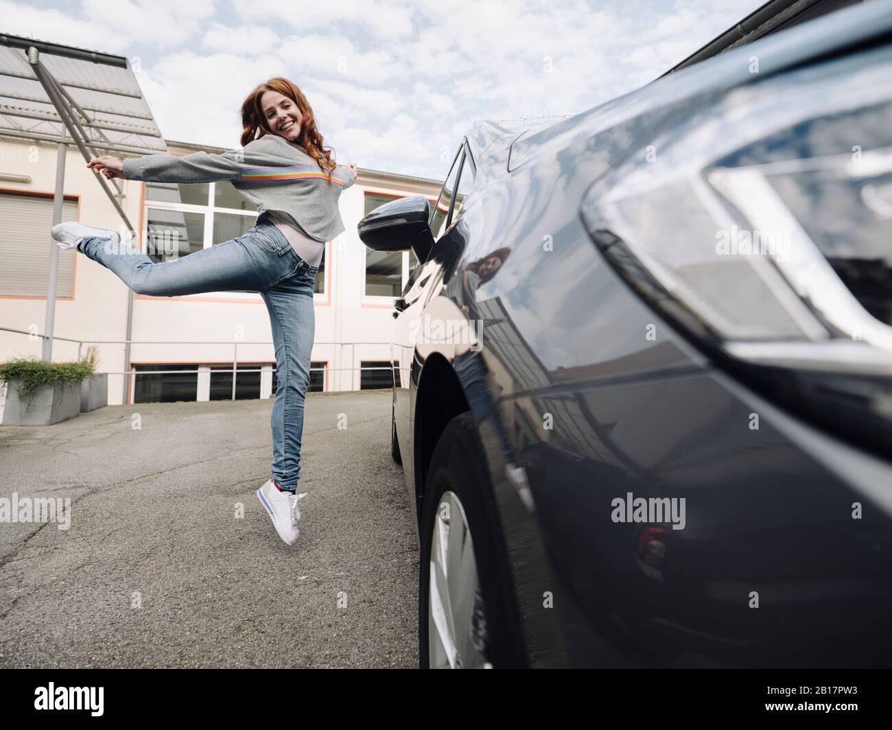 Happy redheaded woman jumping beside car Stock Photo - Alamy