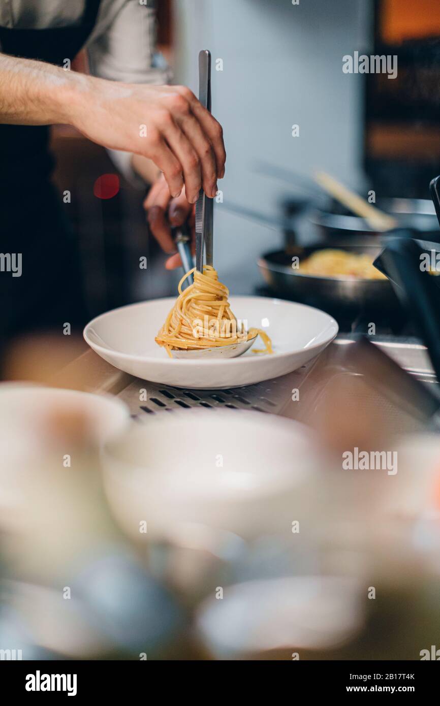 Chef preparing a pasta dish in traditional Italian restaurant kitchen ...