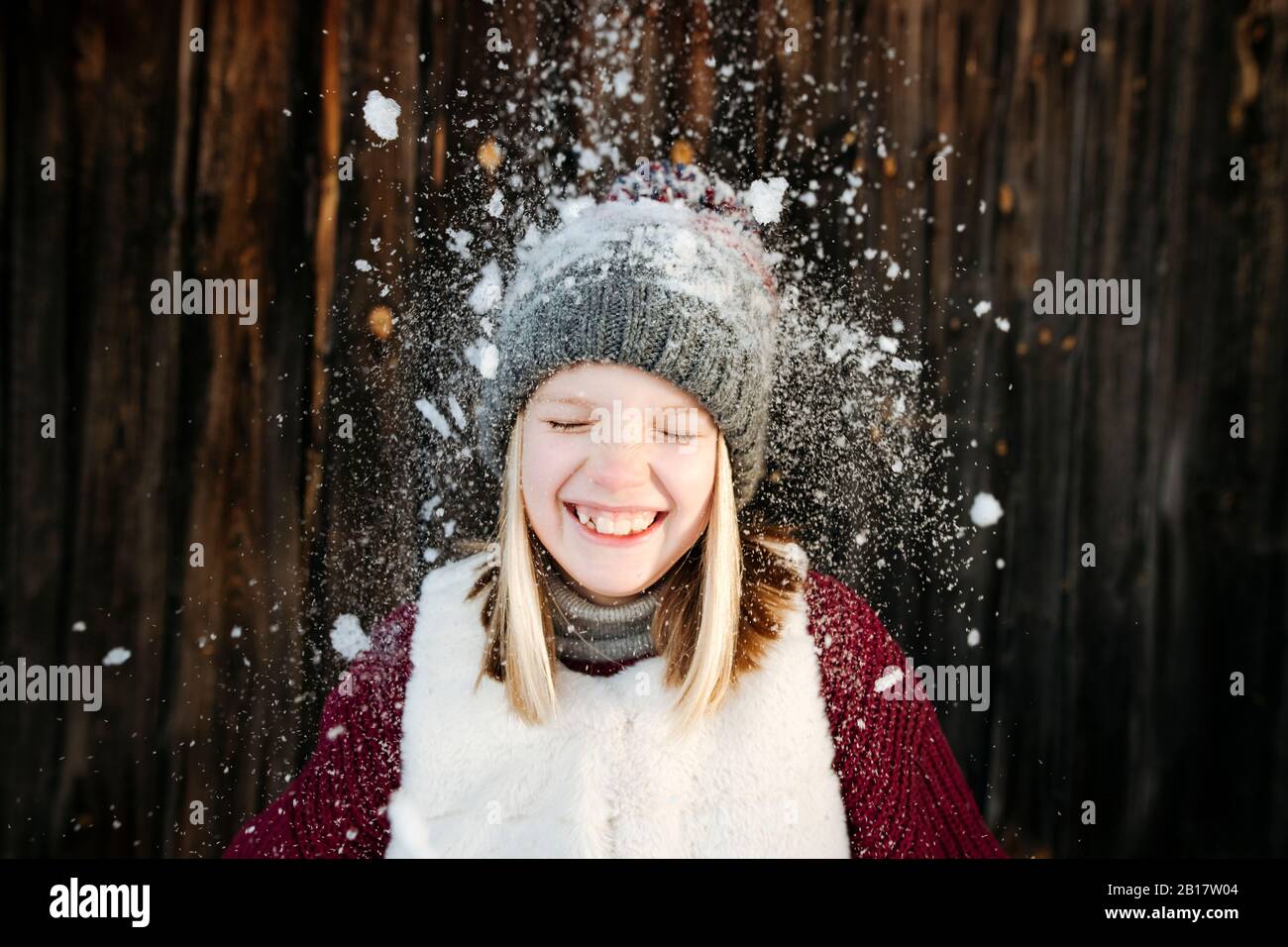 Snow falling on happy girl wearing woolly hat Stock Photo - Alamy