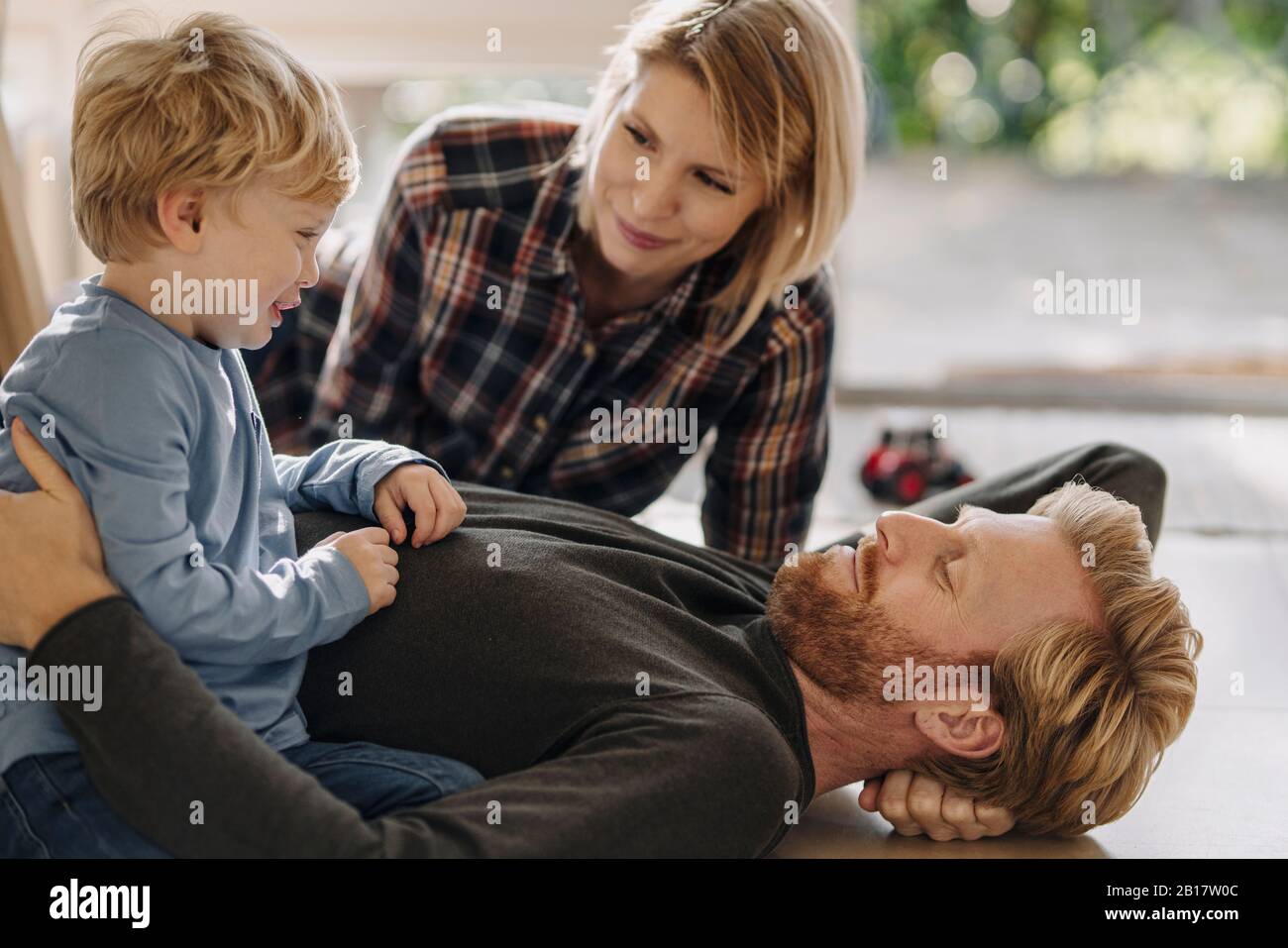 Happy relaxed family lying on the floor together at home Stock Photo ...