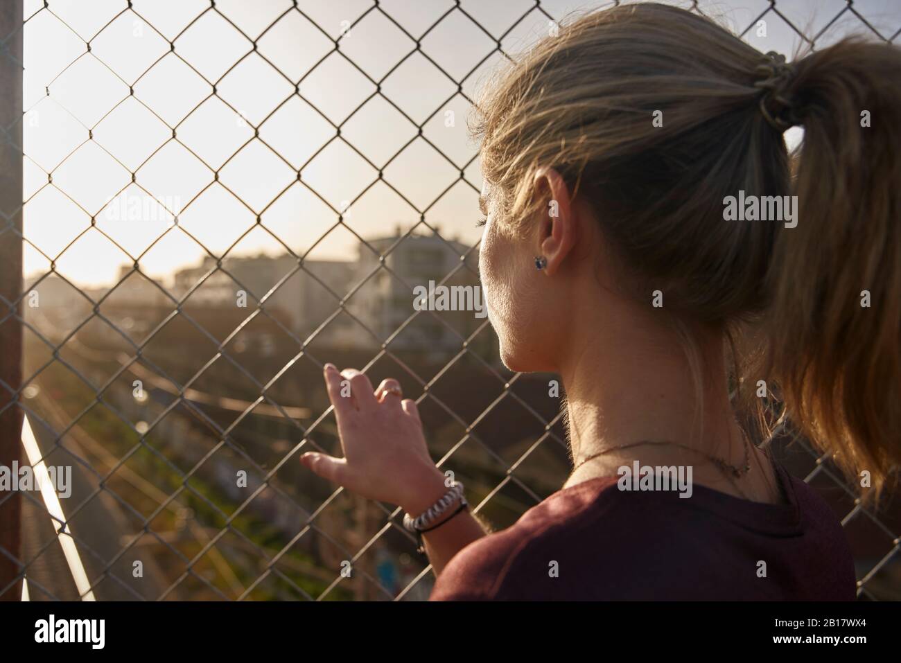 Sporty young woman looking through a fence Stock Photo - Alamy
