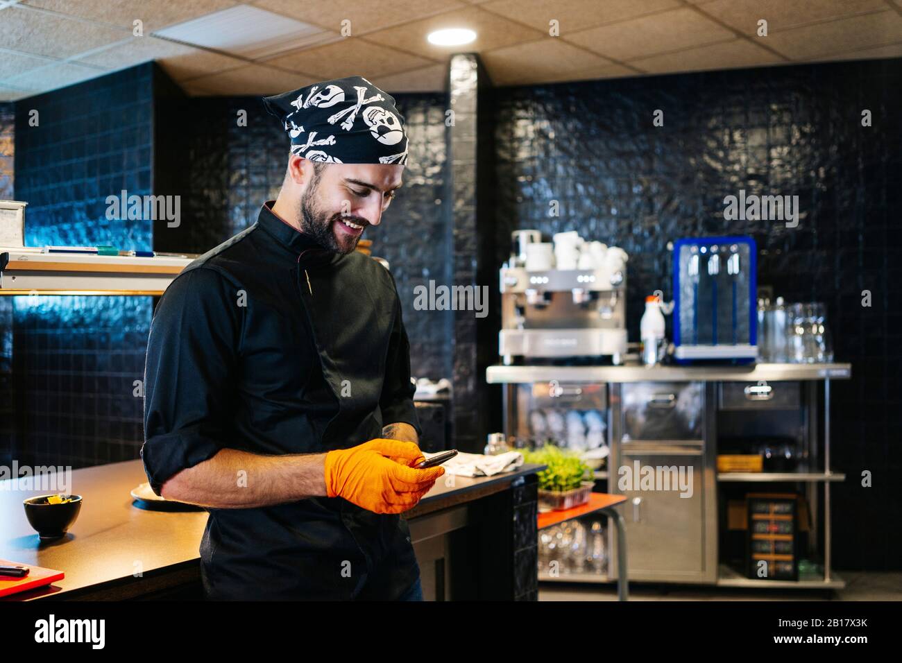 Smiling chef using cell phone in restaurant kitchen Stock Photo - Alamy