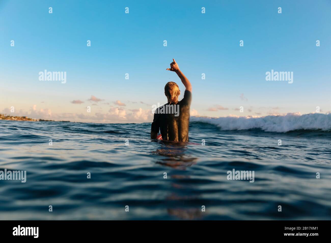 Surfer making surfer sign sitting on surfboard, Bali, Indonesia Stock ...