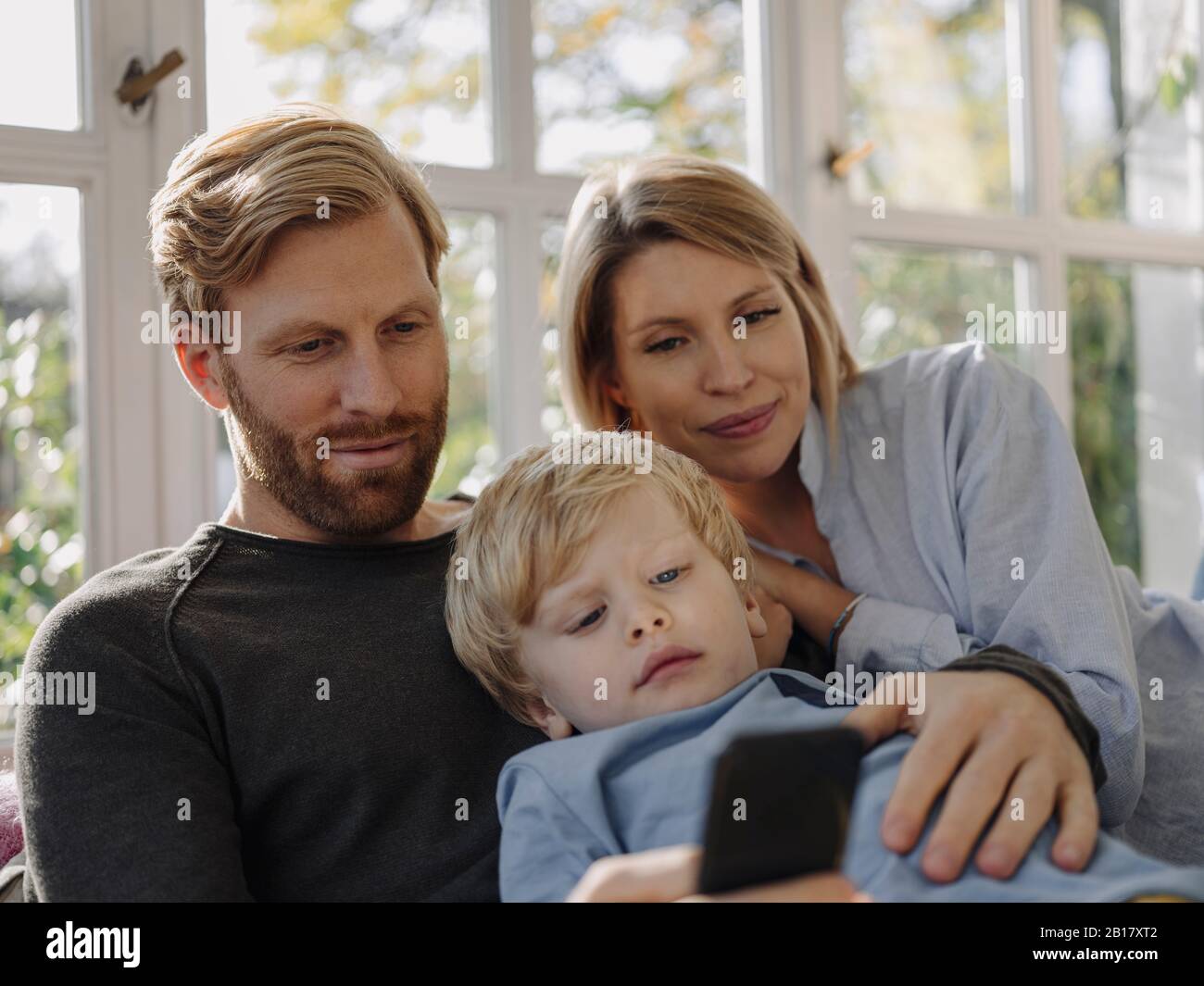 Family using cell phone in sunroom at home Stock Photo - Alamy