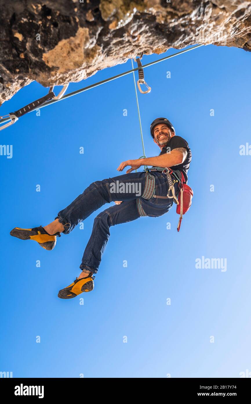 Smiling climber abseiling from rock face Stock Photo - Alamy