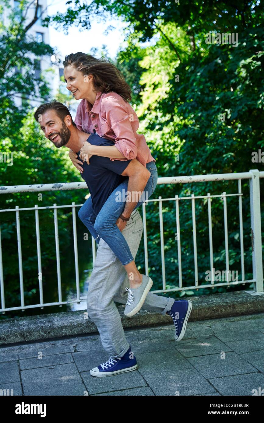 Happy man running and carrying woman piggyback Stock Photo - Alamy
