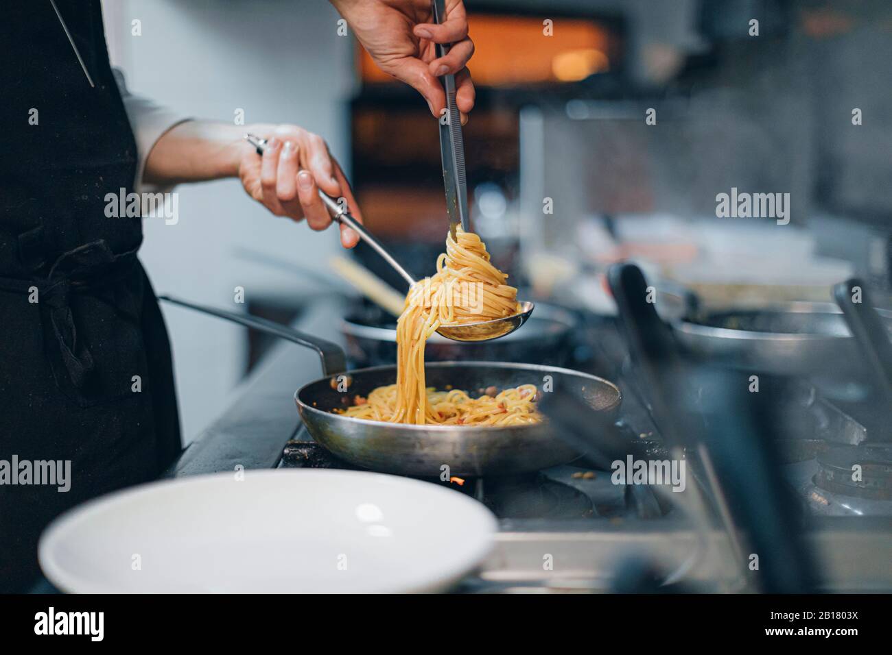 Chef preparing a pasta dish in traditional Italian restaurant kitchen ...
